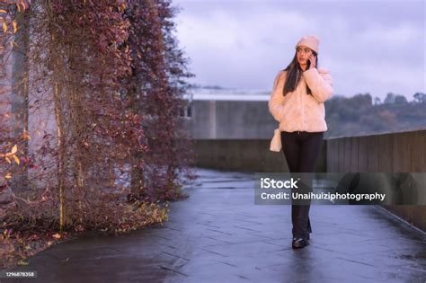 분홍색 울 스웨터와 모자를 쓰고 전화로 전화를 걸면서 도시에서 예쁜 백인 갈색 머리 스트리트 스타일 패션 25 29세에 대한 스톡 사진 및 기타 이미지 Istock