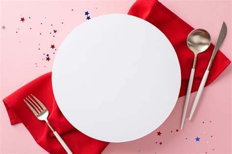 축제 테이블 세팅으로 독립 기념일을 준비하십시오 포크 나이프 숟가락 냅킨 파스텔 핑크를 배경으로 별 모양의 색종이가 보인다 빈 원 개인화된 메시지 또는 광고에 적합 0명에