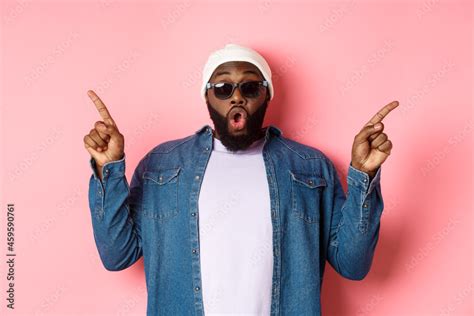 Amazed Cool Black Guy Showing Two Variants Pointing Fingers Sideways