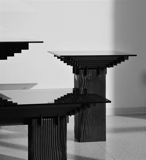 Gridded Steel Frames Slice Through Charred Timber Bases For Lin Tables