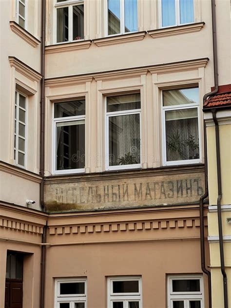 An Old Faded Inscription In Cyrillic Script Is Visible Below The Second Floor Windows