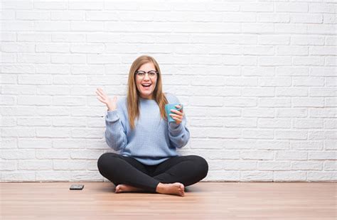 젊은 성인 여자 비명 큰 웃음과 함께 승리를 축 하 하는 커피 매우 행복 하 고 흥분 우승자 표현의 흰색 벽돌 벽 Driking