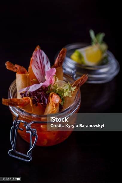 새우 꼬리는 퍼프 페이스 트리에 싸서 튀긴 것입니다 꼬리는 새콤 달콤한 칠리 소스 한 병에 들어 있으며 위에는 식용 파이와 양상추가 있습니다 항아리 뚜껑에 레몬 쐐기가