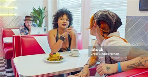 Two Nonbinary People Talking To Each Other On The Booth Of 1950s Styled