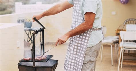 옛날 스타일의 나무와 불에 신선한 고기를 요리하는 남자 손을 닫습니다 바베큐 바베큐 그릴 친구들과 함께 먹고 즐기는 것을 좋아하는 사람들을 위한 가정 축하