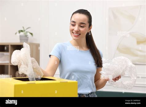 Garbage Sorting Smiling Woman Throwing Plastic Package Into Cardboard Box In Room Stock Photo
