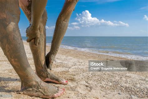 해변 모래에 밝은 빨간 페디큐어와 아름다운 여성의 발에 선택적 초점 손은 발의 발목에 진흙을 치유 하는 얼룩 바다에서 휴식을 취하면서 피부 젊어짐 스파 복사 공간을