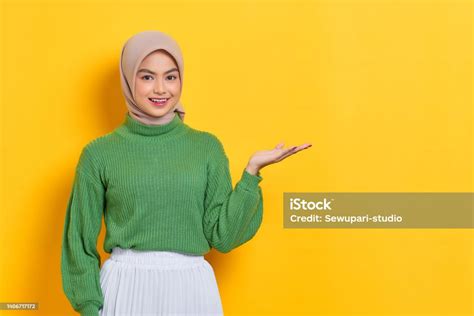 노란색 배경에 고립 된 손바닥에 복사 공간을 제시하는 녹색 스웨터의 쾌활한 아름다운 아시아 여성 20 24세에 대한 스톡 사진 및 기타 이미지 Istock