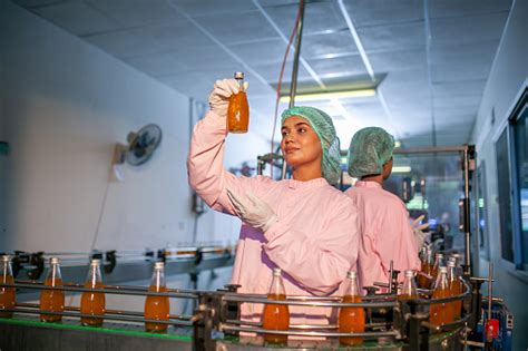 아시아 여성 노동자가 음료 공장의 생산 라인에서 과일 주스의 제품 병을 확인하고 있습니다 제조업체는 식품 산업의 품질을 확인합니다 2명에 대한 스톡 사진 및 기타 이미지