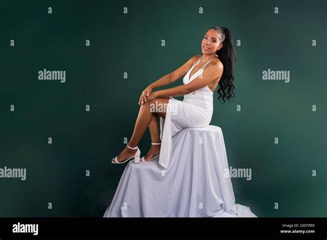 Beautiful Brunette Woman Sitting With Hands On Her Knees Posing For Photo Isolated On Green
