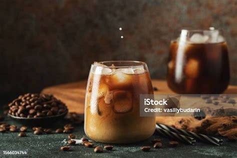 크림이 쏟아진 키가 큰 유리잔에 담긴 아이스 커피 어두운 콘크리트 테이블 위에 얼음 조각과 콩 0명에 대한 스톡 사진 및 기타 이미지 Istock