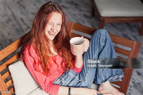 집에서 커피 한 잔과 함께 아늑한 옷을 입고 소파에 앉아있는 행복한 젊은 여성 14 15 살에 대한 스톡 사진 및 기타 이미지 14 15 살 감정 거실 Istock