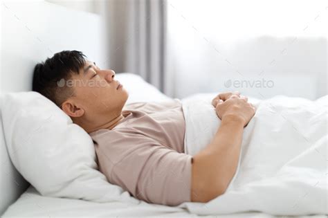 Middle Aged Chinese Man Sleeping Alone In Bed Side View Stock Photo By Prostock Studio
