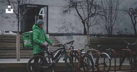 녹색 재킷과 파란색 데님 청바지를 입은 남자가 검은 자전거를 타고 있다 사진 Unsplash의 무료 Москва 이미지