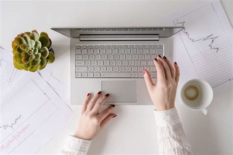 일을 마친 여성 프리랜서는 커피 한 잔과 업무 가 끝나는 빈 음료로 노트북을 닫습니다 그래픽과 차트는 테이블에 누워 종이에 인쇄 플랫 레이 거래자에 대한 스톡 사진 및 기타