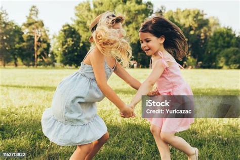 공원의 녹색 잔디에서 춤을 추고 함께 노는 두 어린 소녀의 이미지 공원에서 여름날을 즐기는 아이들 두 자매는 자연 배경에 재미를 어린 시절과 우정 2명에 대한 스톡 사진 및
