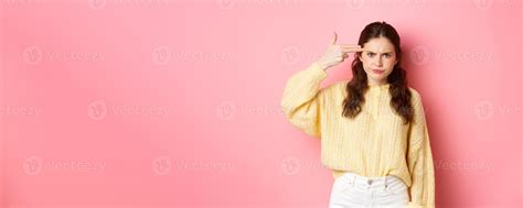 Annoyed And Bothered Girl Frowning Showing Finger Gun Next To Her