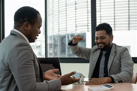 부동산 중개인은 모델 주택의 예를 제공하여 고객에게 주택과 토지를 제시합니다 주택 융자 주택 모델 모기지 대출 제안 및 주택 보험에 관한 소개 2명에 대한 스톡 사진 및