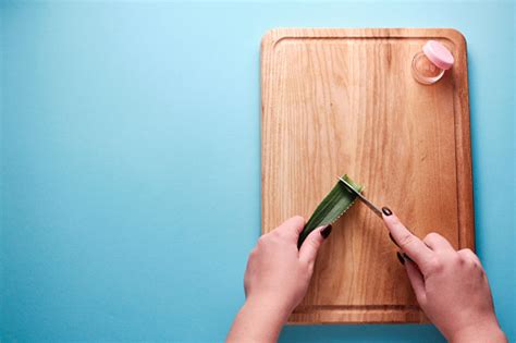 분홍색 모자 파란색 배경 여성의 손의 상단보기 왼쪽의 카피 스페이스가있는 열린 빈 상자 옆에 칼로 알로에 베라 슬라이스를 자르기 건강관리와 의술에 대한 스톡 사진 및 기타