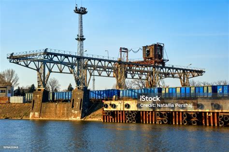 강 항구에 있는 오래된 갠트리 크레인 적재를 기다리는 빈 철도 차량 맑은 날 푸른 하늘 맑은 강물 객차에 대한 스톡 사진 및