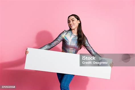 밝은 분홍색 배경에 서서 흰색 빈 배너를 들고 세련 된 광택 있는 상의를 입은 젊은 여자 20 24세에 대한 스톡 사진 및 기타 이미지 20 24세 검정 머리 공란