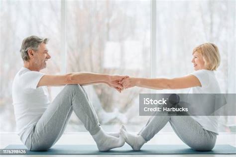 스포츠와 건강한 라이프 스타일 흰색 피트니스 체육관에서 매트에 앉아 서로를 보고 미소를 지으며 스트레칭을하는 스포티 한 중년 부부 건강한 관절과 등 지원 트레이너 요가에