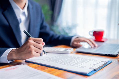 Man은 고객과의 금융 계약서 및 계약 문서를 주의 깊게 검토하여 대출 모기지 투자 기회 신용 조건 및 비즈니스에 대한 세금 영향에 대해 논의했습니다 개념에 대한 스톡 사진