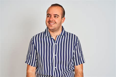 파란 줄무늬 셔츠를 입은 청년은 고립된 흰색 배경 위에 서서 얼굴에 미소를 지으며 자연스러운 표정을 짓고 있습니다 자신감 있게 웃고 있습니다 감정에 대한 스톡 사진 및 기타