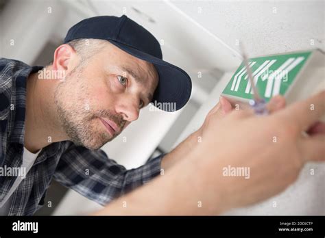 Man Fixing Illuminated Exit Sign To Wall Stock Photo Alamy
