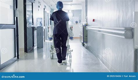 Patient Bed And Nurse Walking In Hospital Hallway Or Corridor To