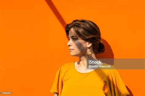 그녀의 얼굴과 몸에 선형 그림자와 노란 블라우스에 아름 다운 젊은 여자 초상화 오렌지 금속 배경입니다 높은 대조와 맑은 날 야외 활동 건강한 생활방식에 대한 스톡 사진 및