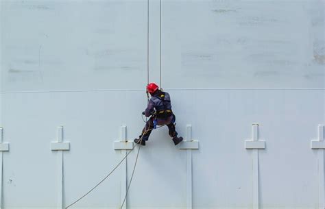 남성 작업자 로프 접근 높이 안전 검사 두께 저장 오일 및 가스 탱크 산업 구름 푸른 하늘 프리미엄 사진