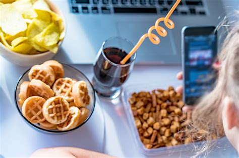 소녀는 패스트 푸드를 먹고 직장에서 스마트 폰에 그것의 사진을 찍는다 건강에 해로운 음식 칩 크래커 사탕 와플 콜라 정크 푸드 개념 감자 요리에 대한 스톡 사진 및 기타