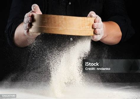 검은 색 유니폼을 입은 한 남자가 둥근 나무 체를 손에 들고 검은 색 배경에 흰 밀가루를 선별합니다 물 빼는 소쿠리에 대한 스톡 사진 및 기타 이미지 Istock
