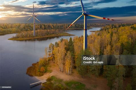 숲 위의 풍차 거대한 풍력 발전기 풍차가 강 위로 솟아 있습니다 터빈이 있는 가을 풍경입니다 풍력 에너지 일몰 전에 풍력 발전 단지 녹색 에너지 자원 개념을 얻기 3d