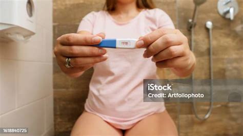 화장실에 앉아 있는 동안 카메라에 두 줄무늬가 있는 긍정적인 임신 테스트를 보여주는 젊은 임산부의 클로즈업 30 34세에 대한 스톡 사진 및 기타 이미지 Istock