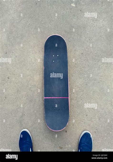 Scrached Up Pink Skateboard Laying On Smooth Concrete Surface At Local Skatepark Black
