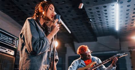 남자는 기타를 연주하고 여자는 노래합니다 백인 소녀와 함께 스튜디오에서 리허설을 하는 아프리카계 미국인 남자 사진 Unsplash의 우크라이나 이미지