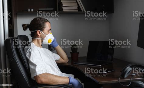 보호복 의료용 마스크 고무 장갑을 착용한 남자가 집에 앉아 검역 중에 노트북과 함께 작업합니다 남자 디자이너 예술가 건축가
