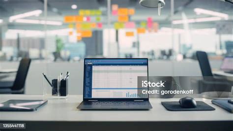 현대 크리에이티브 오피스의 책상 위에 서 있는 금융 분석 스프레드시트 응용 프로그램노트북 컴퓨터 다채로운 계획 노트와 배경 유리 벽에 사무실에 대한 스톡 사진 및 기타