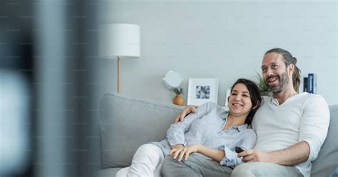 백인 사랑하는 부부는 집 거실에서 함께 영화를 본다 아름 다운 행복 한 새 결혼 남자와 여자는 소파에 앉아 원격 제어 Tv 쇼를 사용 하 고 집에서 텔레비전에 재미 웃음