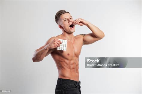 근육질의 몸매를 가진 강하고 잘생긴 운동 피트니스 남자가 흰색 배경에 알약 팩과 음료 알약을 들고 있습니다 스포츠 및 보충제 비타민과 건강 30 34세에 대한 스톡 사진 및