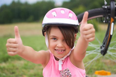 매력적인 작은 사이클 엄지손가락을 포기 두 손으로 야외를 배경 몸짓 엄지손가락에 자전거와 함께 행복 한 즐거운 작은 소녀 어린이 긍정적인 정서 및 라이프 스타일 감정에 대한