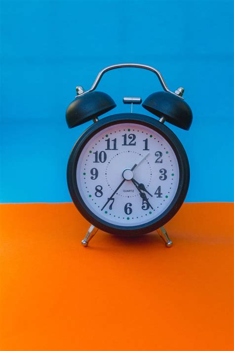 Free Picture Analog Black Alarm Clock In A Vintage Style On An Orange And Blue Surface Free Picture Analog Black Alarm Clock In A Vintage Style On An Orange And Blue Surface