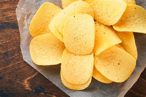 감자 골판지 칩 패스트 푸드 파삭 파삭 한 감자 칩은 오래된 부엌 테이블 나무 배경에 나무 스탠드에 사워 크림 소스와 양파와