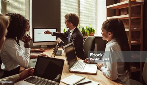 프로젝트 프레젠테이션 사업가는 사무실에서 젊은 팀의 회의 동안 컴퓨터 모니터의 흰색 화면을 가리킵니다 민족 다양성 개념 착색 된 이미지 계획에 대한 스톡 사진 및 기타