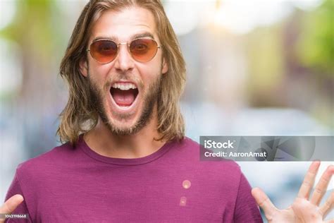 이상의 선글라스를 입고 긴 머리를 가진 젊은 잘생긴 남자 절연 배경 미친을 축 하 하 고 무기와 성공을 위한 흥분 비명 제기 및