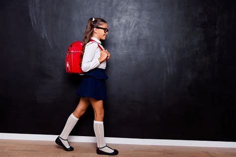 전체 크기 몸 길이 프로필 측면 보기 좋은 스마트 귀여운 세련 된 작은 소녀의 흰 블라우스 셔츠와 블루 스커트 빨간 가방에에서