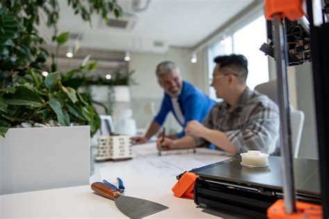 Two Men Architects Using 3d Printer In Office And Projecting House Drawing Blueprints Stock