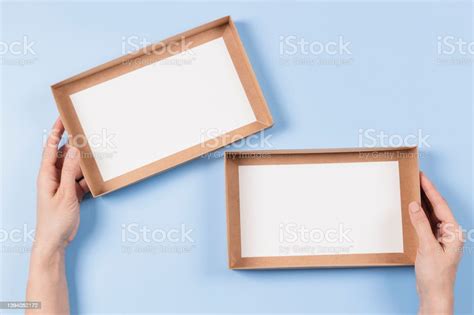 밝은 파란색 배경에 빈 갈색 판지 상자를 들고있는 여성 손의 상단보기 모형 소포 상자 포장 쇼핑 배달 개념 손에 대한 스톡 사진